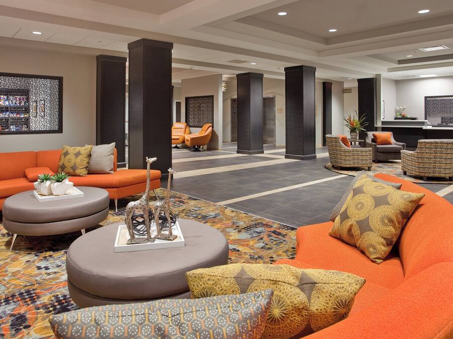 Um lobby moderno com um conjunto de sofás, uma mesa de centro e uma estátua decorativa de girafa.