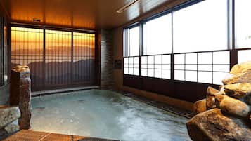 Um onsen japonês tradicional com vista para as montanhas através de um ecrã shoji.