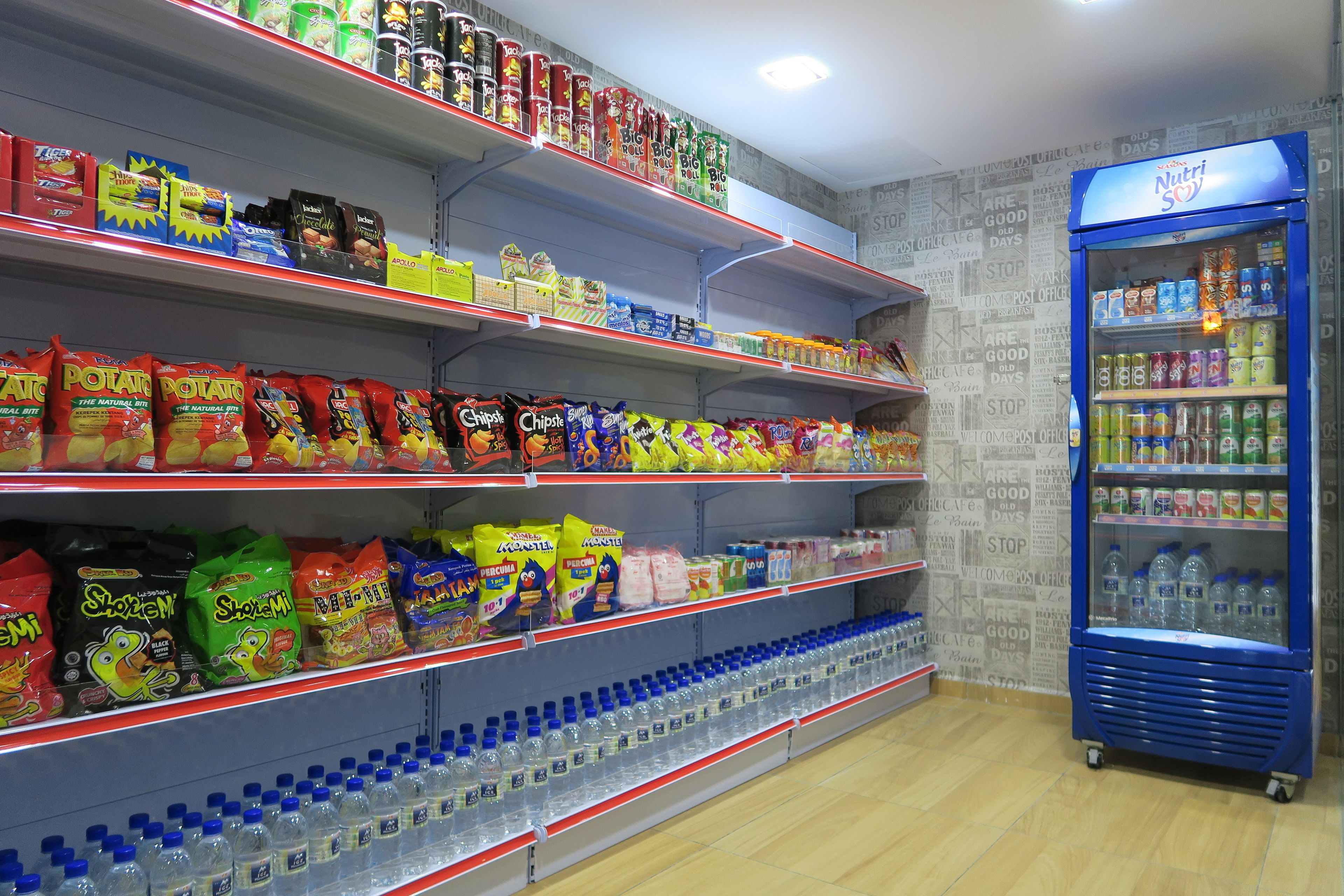 Um corredor de supermercado com prateleiras cheias de lanches, salgadinhos e água engarrafada.