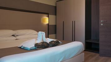 Quarto de hotel com uma cama, um guarda-roupa e uma mesa de cabeceira com abajur.