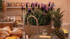 Buffet com doces, cesta de vime com flores e uma abacaxi.