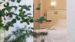 Um quarto com cama, mesas de cabeceira e um criado-mudo.