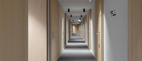 Corredor moderno de hotel com portas de madeira e carpete cinza.