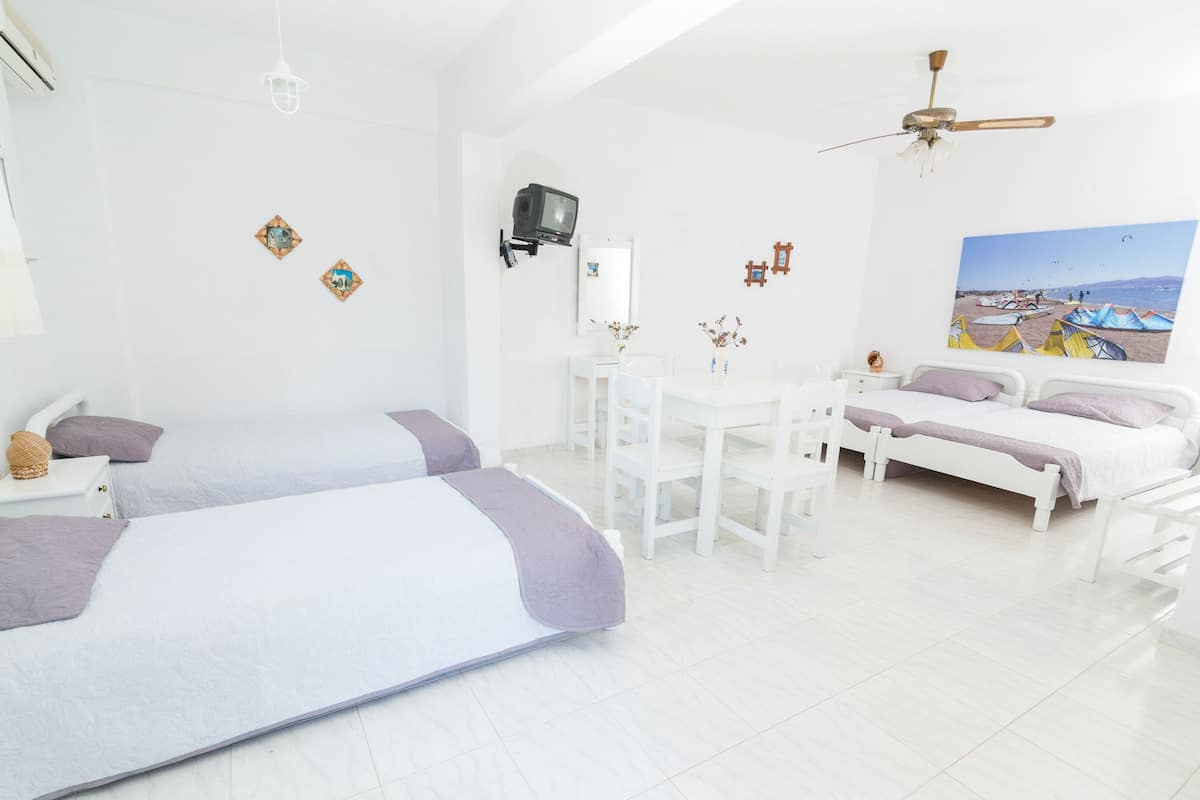 Quarto com duas camas, uma escrivaninha e um ventilador de teto.