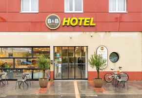 Um hotel tipo bed and breakfast com fachada vermelha, entrada de vidro, área de estar ao ar livre e uma bicicleta estacionada em frente.