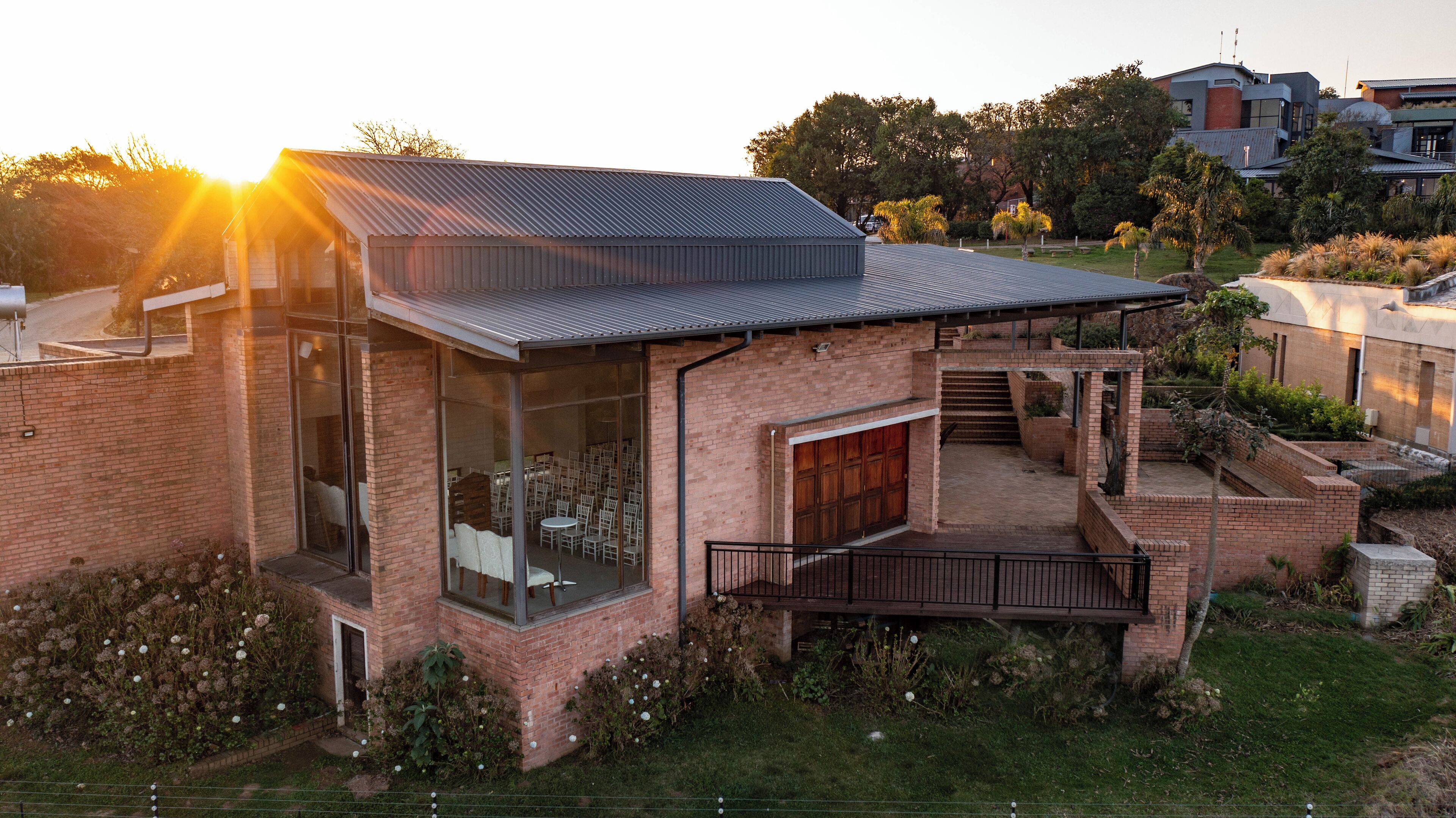 Uma casa moderna com fachada de vidro, exterior de tijolo e telhado de metal.