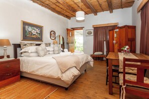 Quarto com cama, piso de madeira, uma mesa de jantar e uma cadeira.