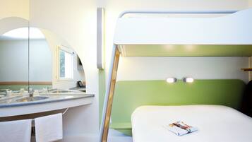 Quarto de hotel compacto com uma cama beliche, uma pia com espelho e uma pequena mesa de cabeceira.