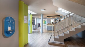 Um interior moderno com uma escadaria, uma parede amarelo vibrante e uma placa para um centro esportivo inteligente.