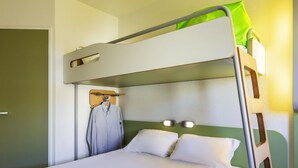 Uma cama beliche com cabeceira verde, colchão branco e um cabide de madeira com uma camisa.