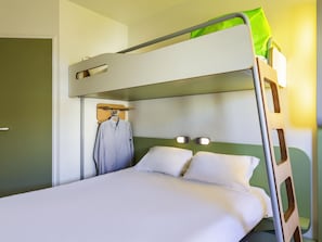 Uma cama beliche com cabeceira verde, colchão branco e um cabide de madeira com uma camisa.