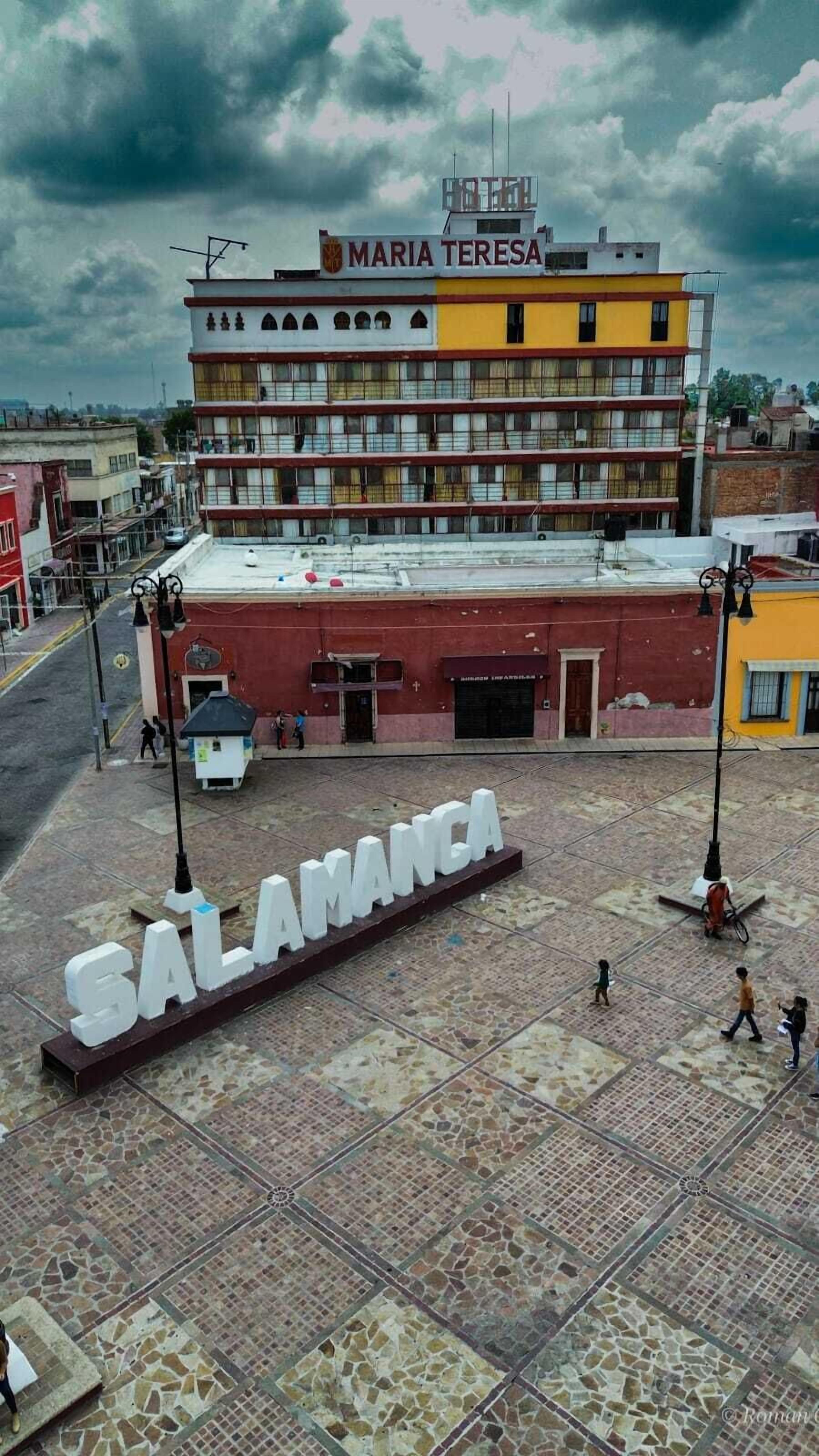 Um edifício com uma placa indicando 'MARIA TERESA' e uma grande placa no chão que diz 'SALAMANCA'.