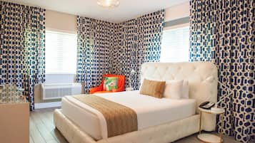 Um quarto com uma cama grande, uma mesa de cabeceira com abajur, uma cadeira e cortinas estampadas.