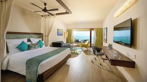 Quarto de hotel com cama, escrivaninha, cadeira, televisão e varanda com vista.