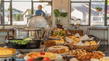 Buffet com diversos alimentos, incluindo frutas, doces e um bolo grande.