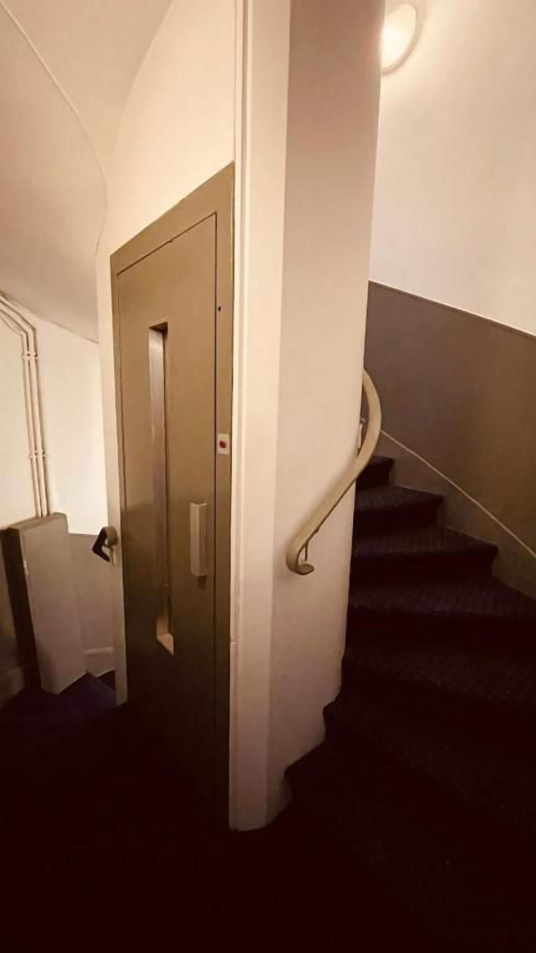 Uma escada com corrimão, uma porta e um acessório de iluminação.