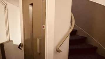 Uma escada com corrimão, uma porta e um acessório de iluminação.
