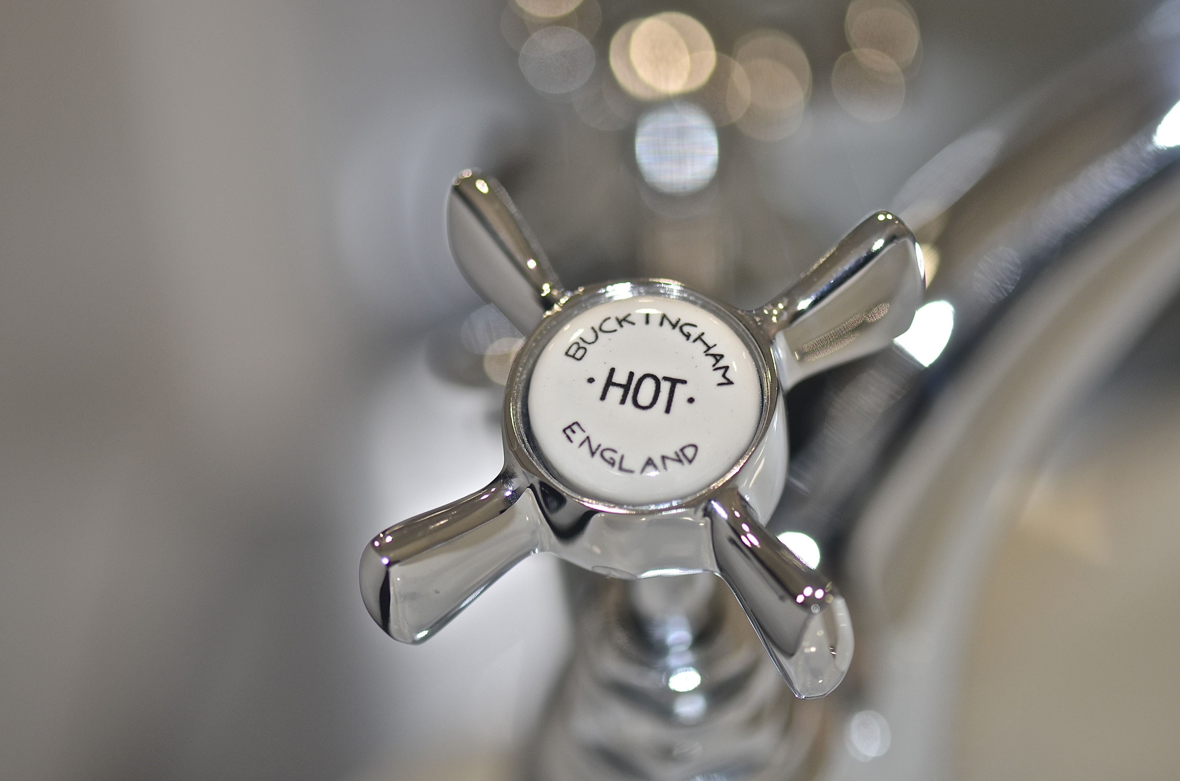 Close-up de uma torneira prateada com a inscrição 'BUCKINGHAM HOT ENGLAND'.