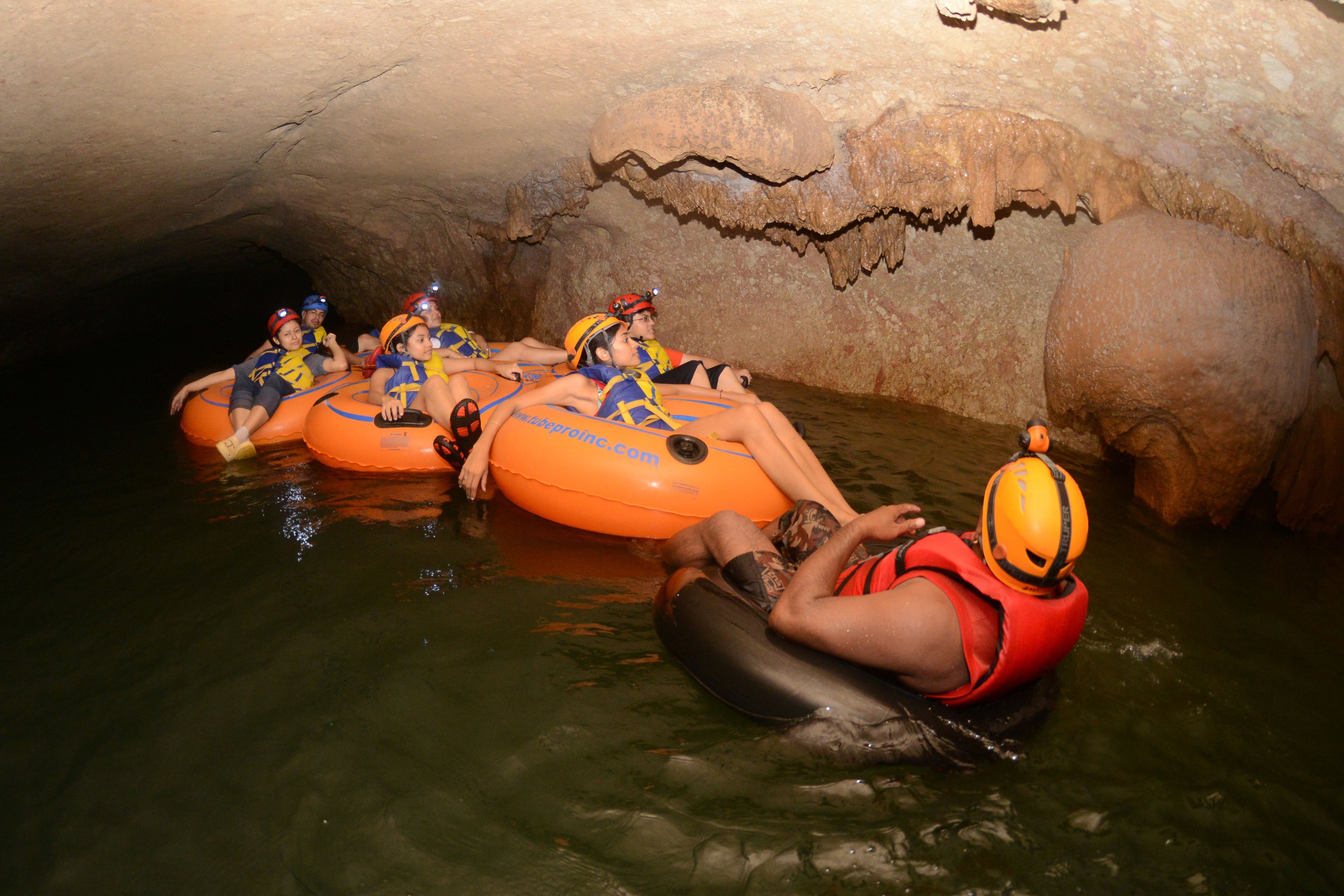 Pessoas em bóias flutuantes em uma caverna com água.