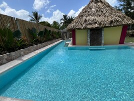 Uma piscina cristalina com uma construção de telhado de palha por perto.
