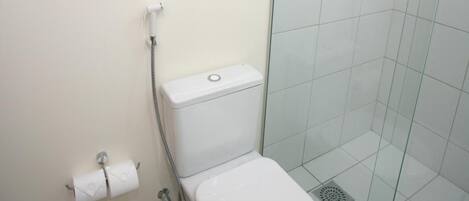 Um banheiro pequeno e moderno, com box de vidro, vaso sanitário e porta-toalhas com duas toalhas.