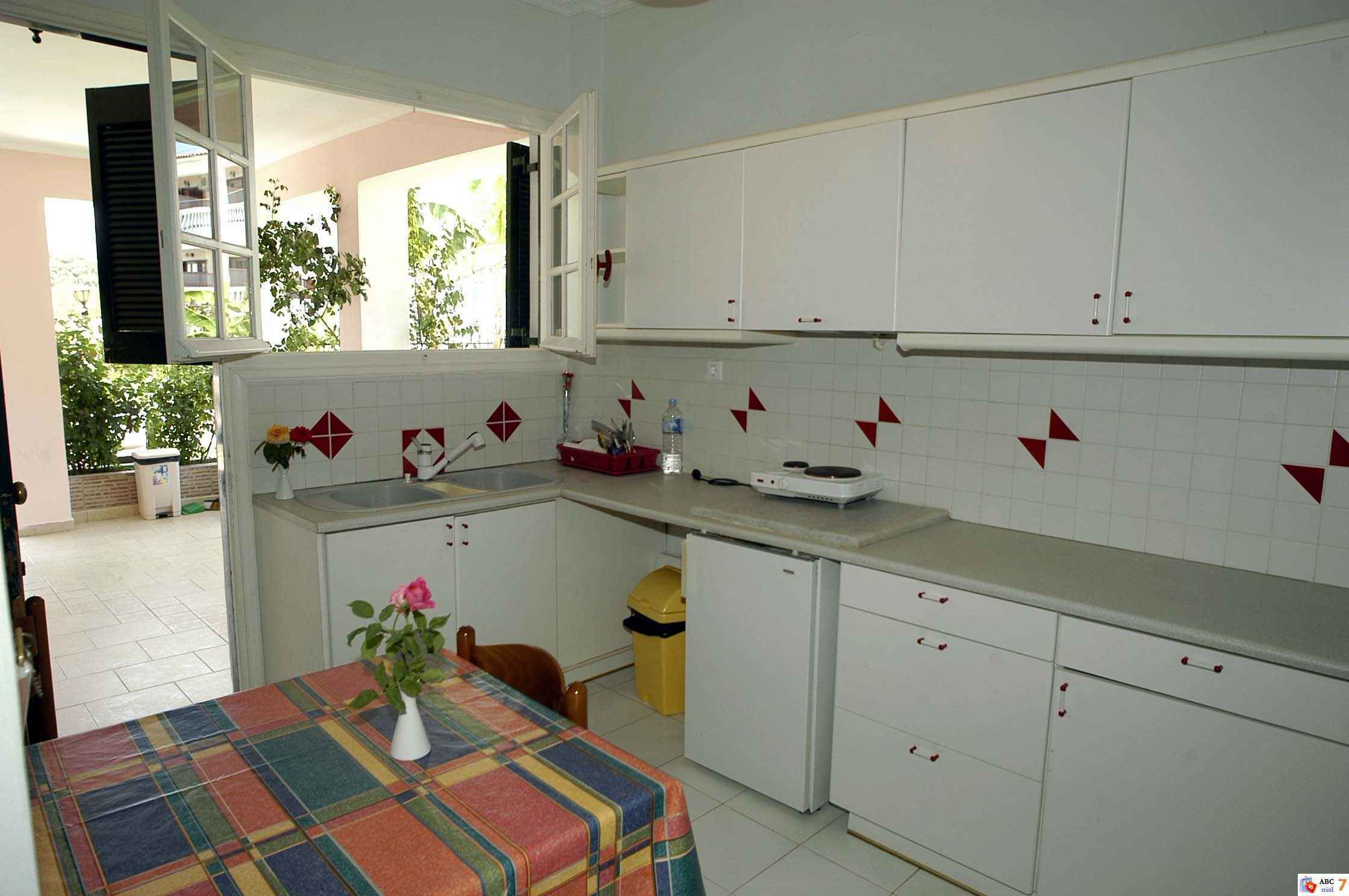Cozinha com armários brancos, painel de azulejos e área de refeições com mesa posta para dois.