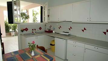 Cozinha com armários brancos, painel de azulejos e área de refeições com mesa posta para dois.