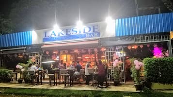 Um bar chamado 'LAKESIDE BAR' com mesas ao ar livre e plantas em vasos.