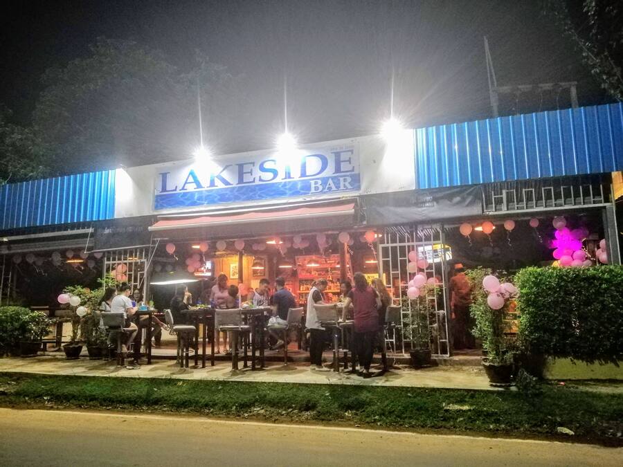 Um bar chamado 'LAKESIDE BAR' com mesas ao ar livre e plantas em vasos.