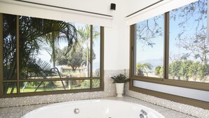 Um banheiro moderno com uma banheira grande, uma planta em vaso e grandes janelas com vista para o exterior.