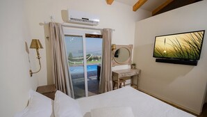 Quarto de hotel com cama, escrivaninha, televisão e vista para o exterior.