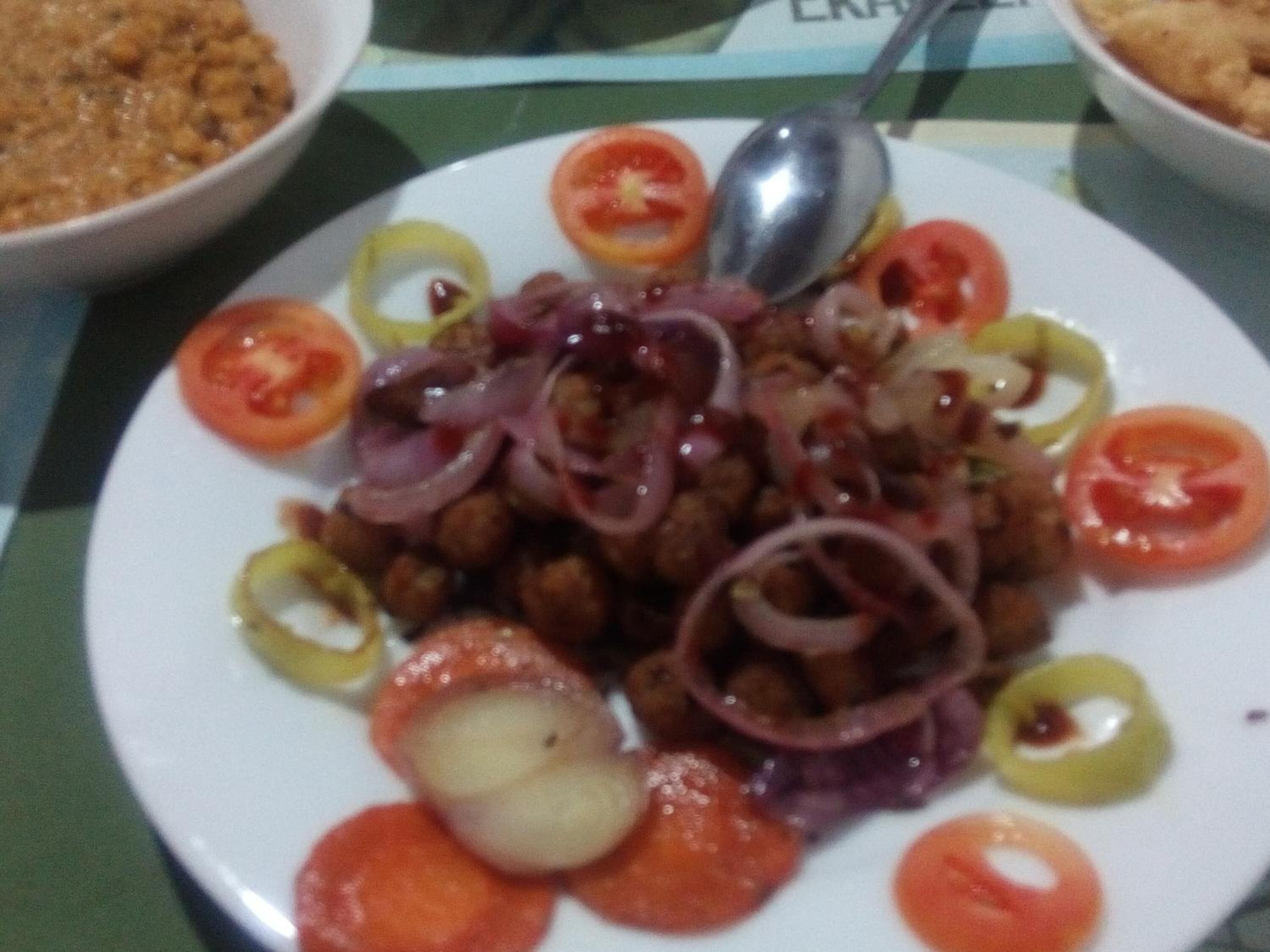 Um prato com tomates fatiados, cebolas e azeitonas.