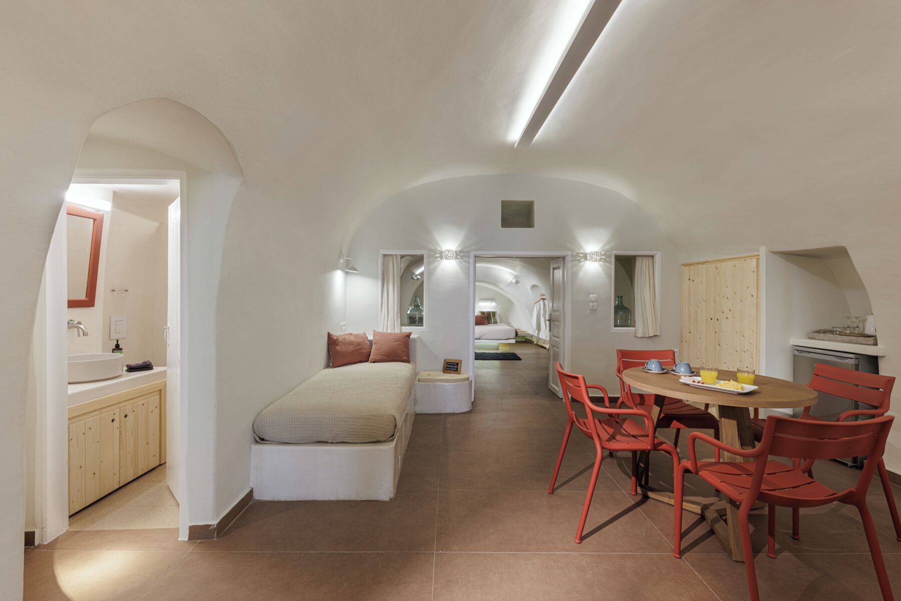 Espaço interior compacto e moderno, com área de refeições, cozinha e espaço para dormir.