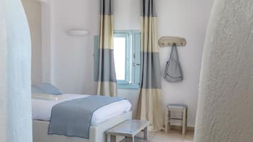 Quarto com cama, um banco, cortinas e um banquinho.