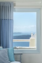 Quarto com vista para uma paisagem costeira através de uma janela.