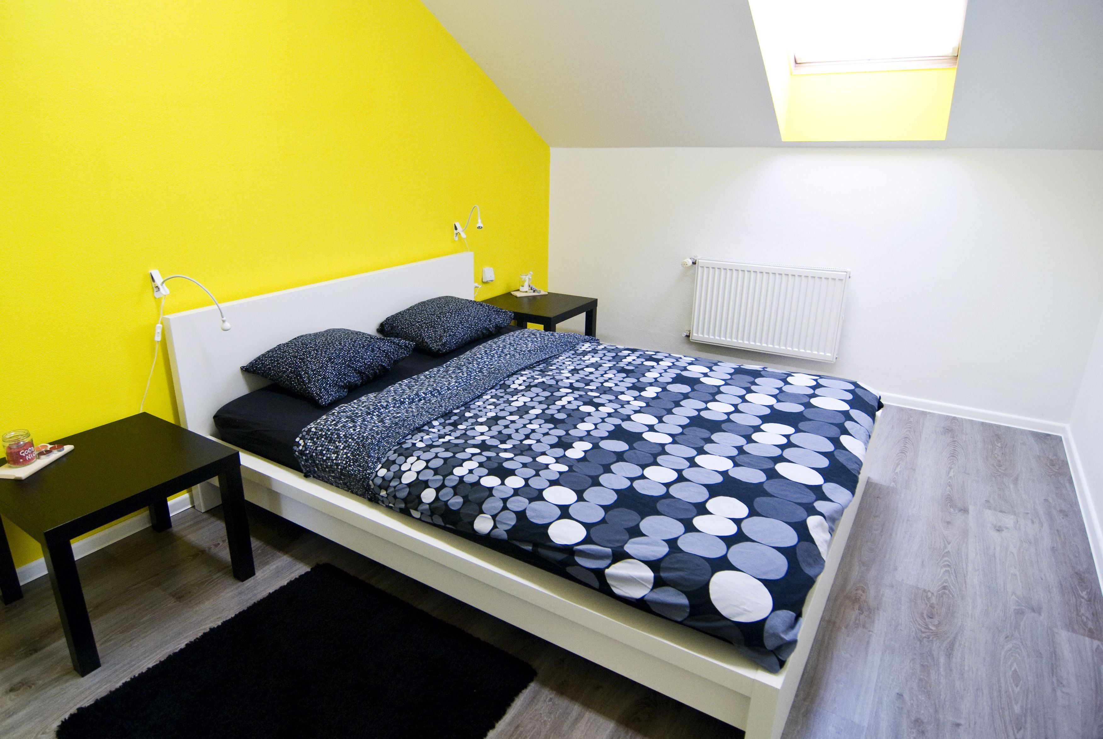 Um quarto moderno com uma cama, uma mesa de cabeceira, uma mesinha e um clarabóia.