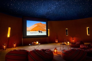 Um cinema acolhedor com teto estrelado, uma tela grande e assentos confortáveis.