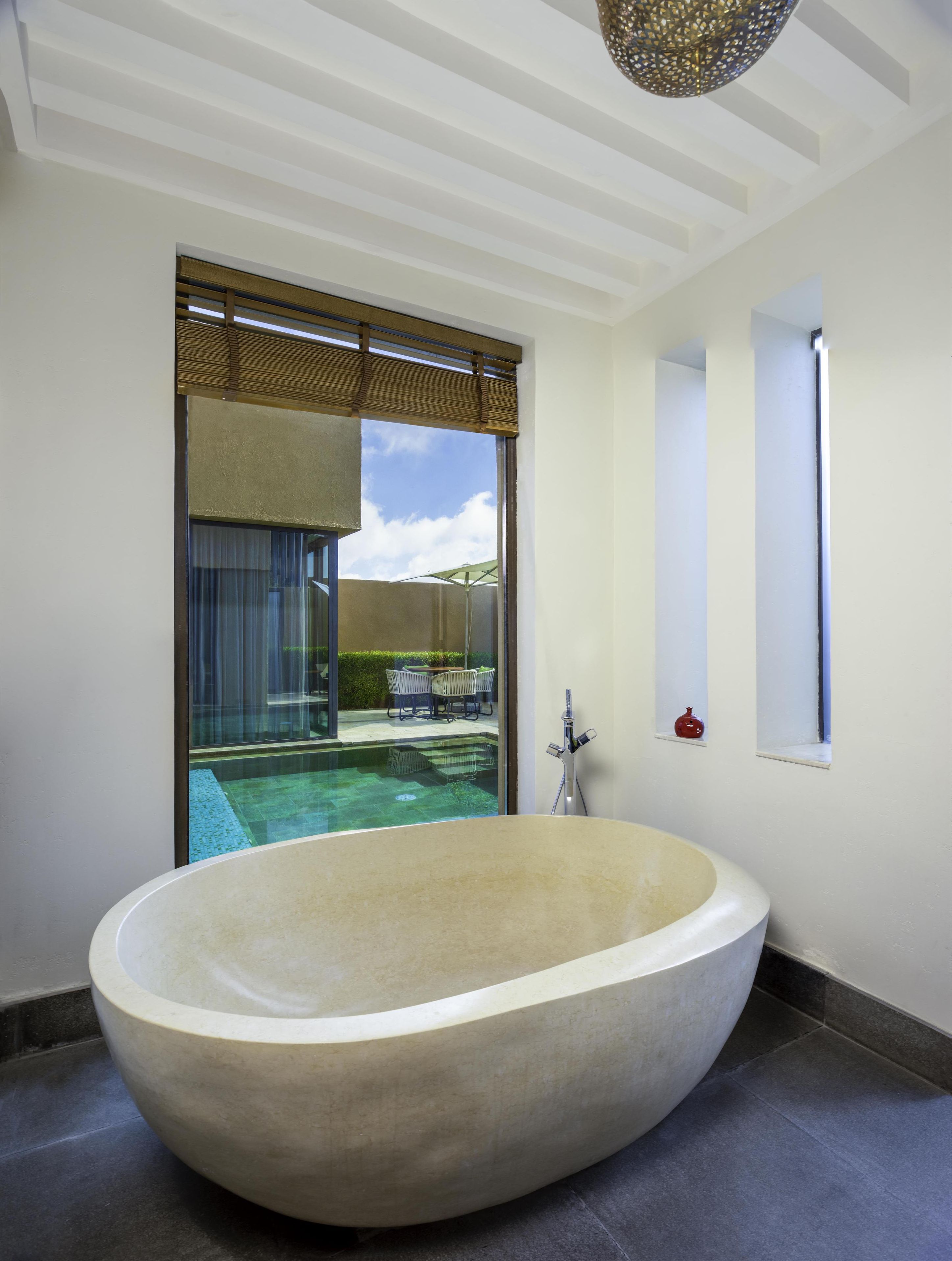 Casa de banho moderna com uma banheira independente grande, uma janela com vista para uma piscina e área de duche.