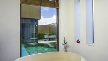 Casa de banho moderna com uma banheira independente grande, uma janela com vista para uma piscina e área de duche.