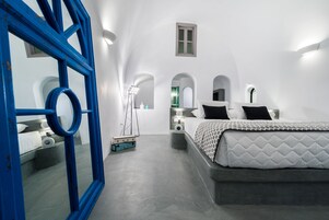 Um quarto moderno com uma cama grande, um espelho com moldura azul e uma janela pequena.