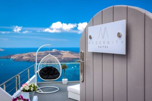 Uma suíte moderna com vista para o mar, uma cadeira suspensa e uma placa com a inscrição "Modernity Suites".
