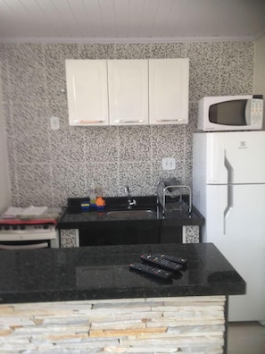 Um frigorífico, um micro-ondas, um forno, utensílios de cozinha 