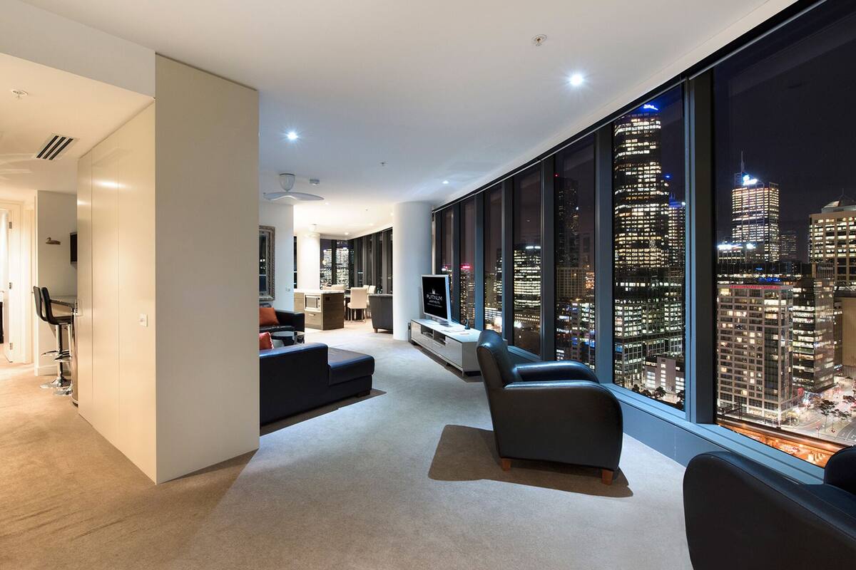Sala de estar moderna com uma janela grande que oferece vista da cidade à noite.