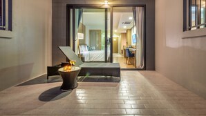 Quarto de hotel moderno com varanda, uma cama, uma escrivaninha e uma cadeira.