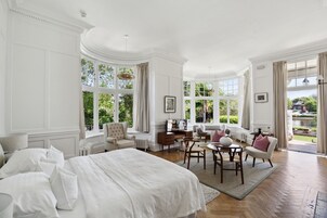 Um quarto espaçoso com uma cama grande, uma escrivaninha e um espaço de estar junto à janela.