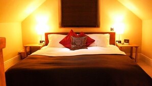 Quarto de hotel com uma cama, duas mesas de cabeceira e uma TV fixada na parede.