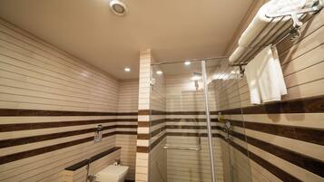 Um banheiro moderno com paredes de azulejos listrados, box de vidro, vaso sanitário e porta-toalhas.