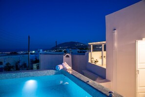Piscina no terraço com vista para a paisagem urbana e uma montanha ao entardecer.