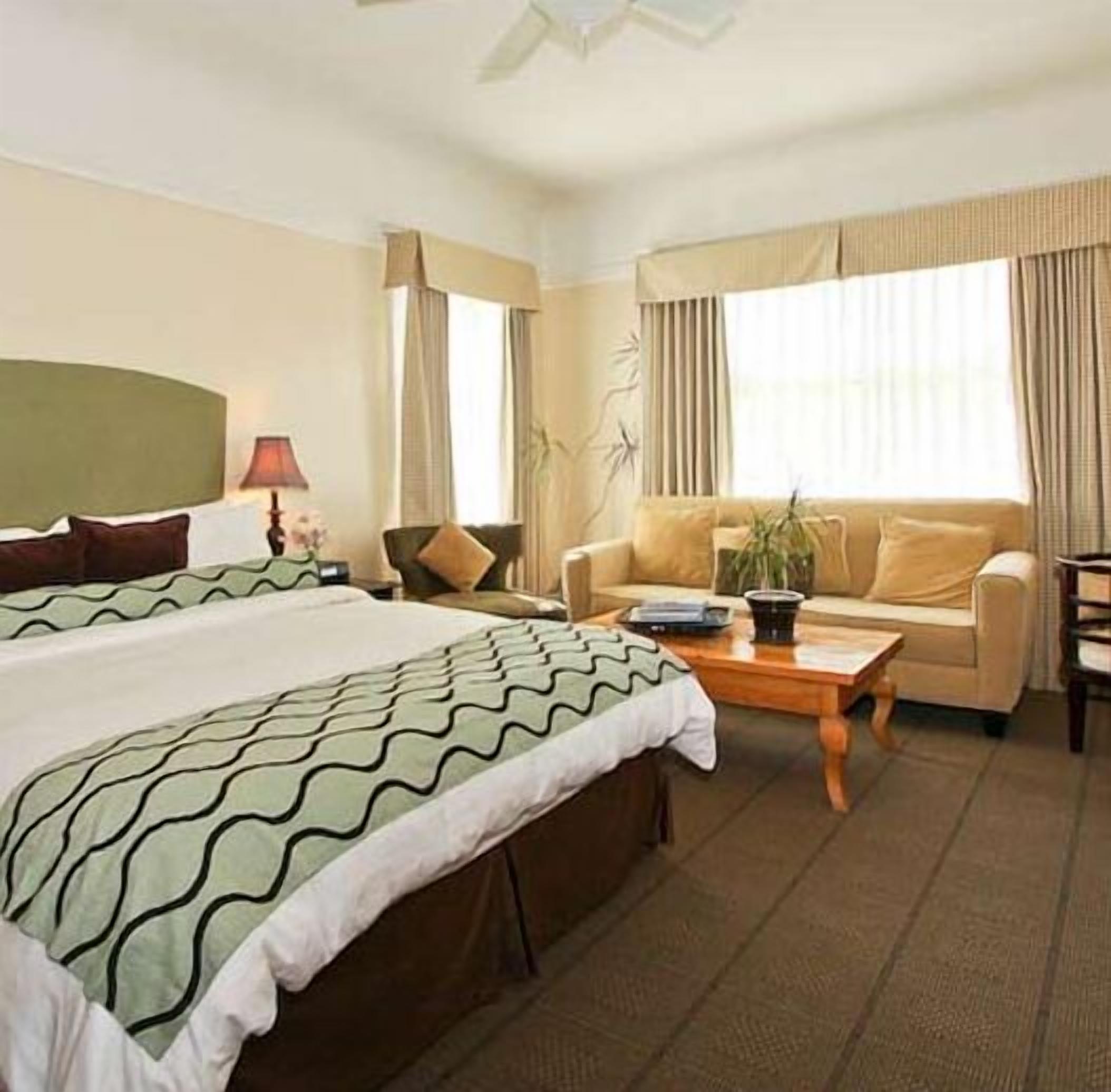 Quarto de hotel com uma cama grande, um sofá, uma mesa de centro e um abajur.