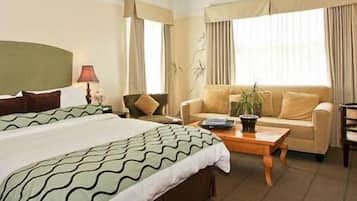 Quarto de hotel com uma cama grande, um sofá, uma mesa de centro e um abajur.